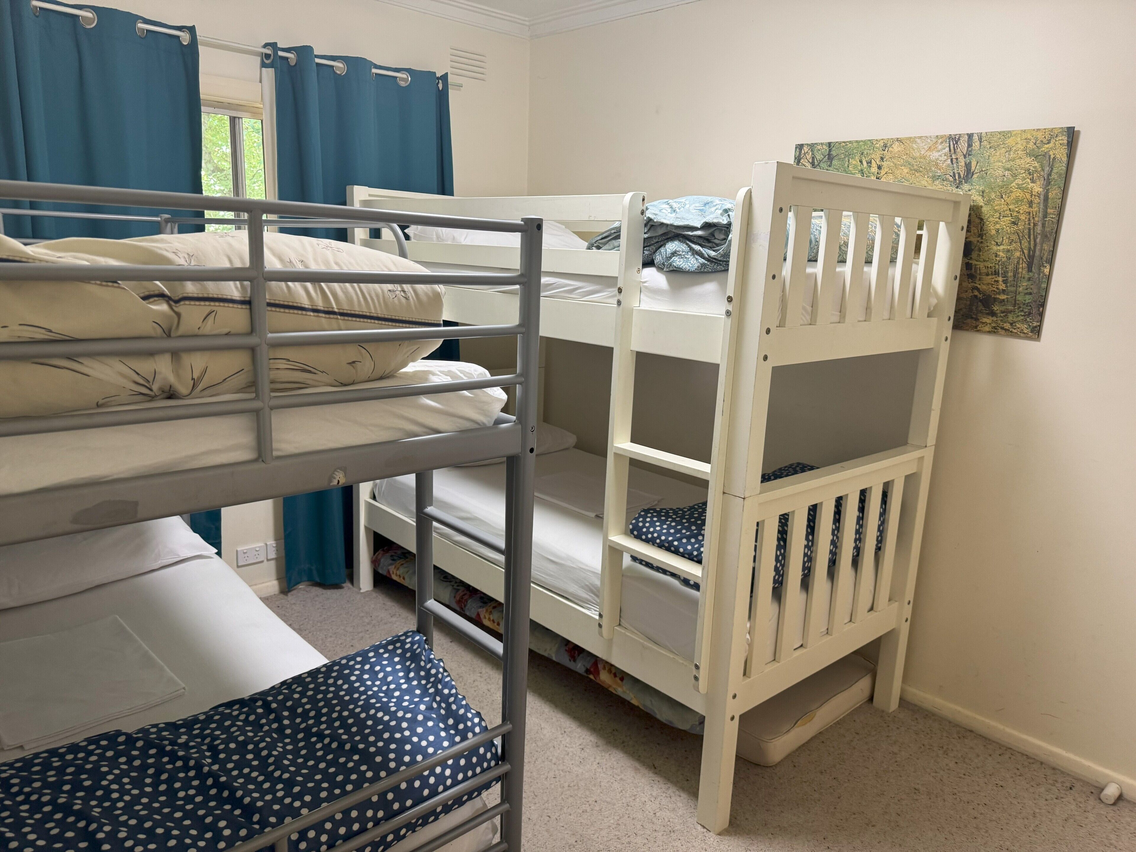 Quarto com beliches, uma janela com cortinas e um quadro na parede.