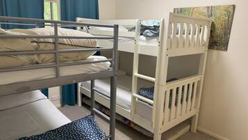 Quarto com beliches, uma janela com cortinas e um quadro na parede.