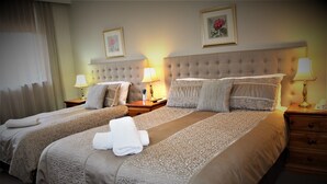 Quarto de hotel com duas camas, cada uma com cabeceira, mesas de cabeceira e abajures, além de almofadas decorativas.