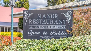 Placa indicando o Restaurante Manor nos Jardins Cotswold, aberto ao público.