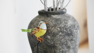 Uma pequena estatueta de pássaro pousada em um vaso preto.
