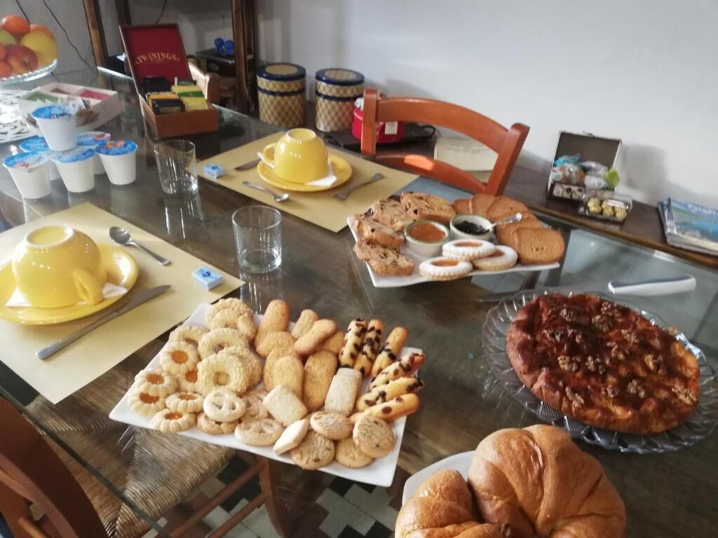 Uma mesa de jantar com diversos alimentos, incluindo doces, uma torta e um croissant.