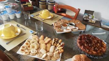 Uma mesa de jantar com diversos alimentos, incluindo doces, uma torta e um croissant.