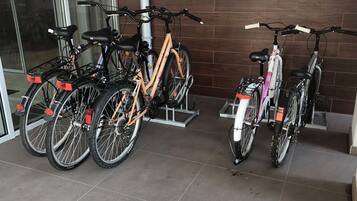 Bicicletas estacionadas em ambiente interno com piso de azulejos e parede de madeira.