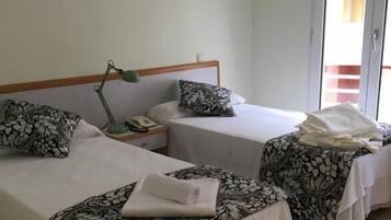 Quarto de hotel com duas camas, cada uma com colcha estampada, abajur e travesseiro.