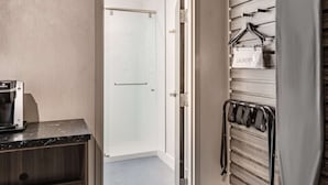 Uma casa de banho moderna com chuveiro, porta-toalhas e máquina de café.