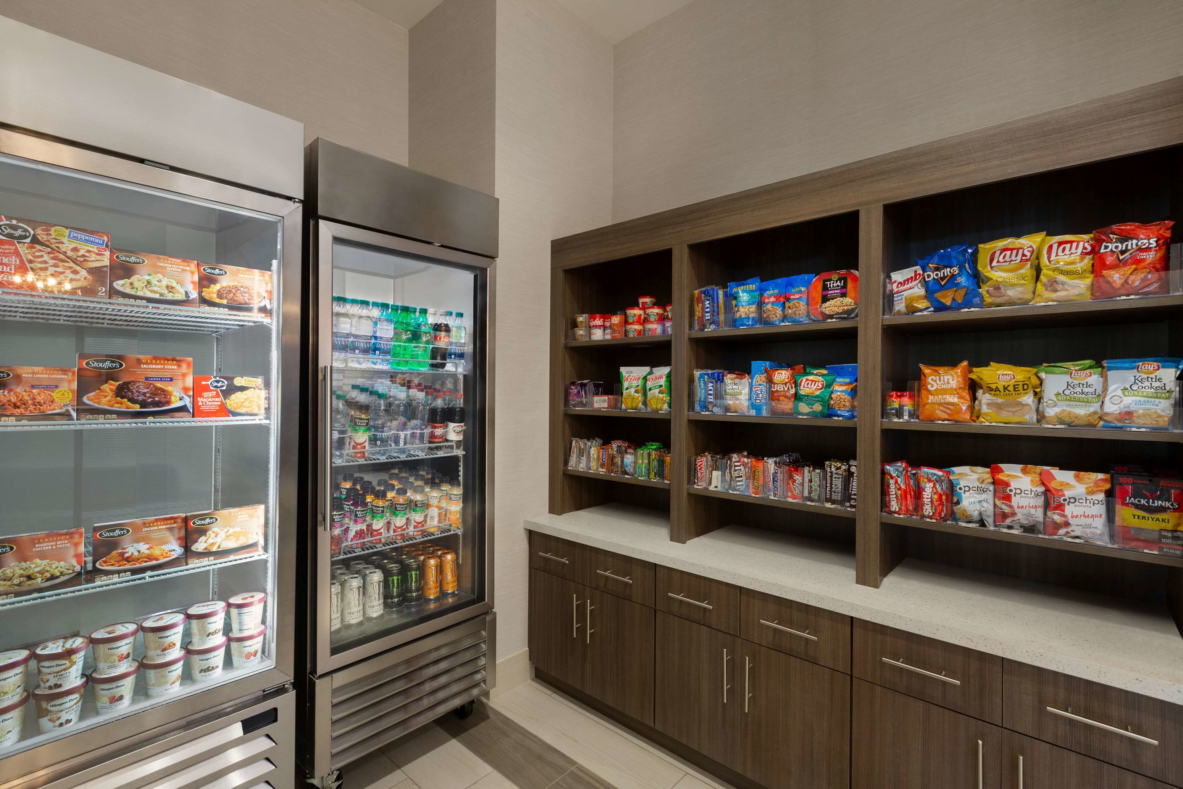 Uma vitrine refrigerada com diversos alimentos e uma despensa abastecida com lanches e bebidas.