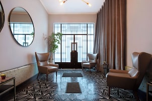 Quarto moderno com duas poltronas de couro, um espelho grande e um chão com padrão geométrico.