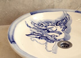 Uma pia de cerâmica com um desenho floral azul.