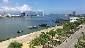 Um rio com barcos, uma ponte e edifícios ao fundo.
