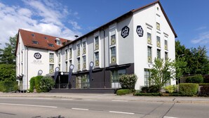 Um hotel com fachada branca, diversas janelas e uma placa com a inscrição 'hotel aura'.