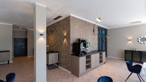 Sala de estar moderna com piso em padrão herringbone, um móvel central de entretenimento e uma área de jantar com cadeiras azuis.