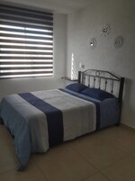 Quarto com cama, janela com persianas e detalhes decorativos nas paredes.
