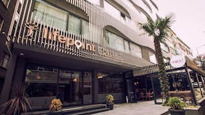 Um hotel com fachada moderna, grandes janelas de vidro e áreas de estar ao ar livre.