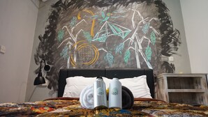Uma cama com um edredom colorido, um travesseiro branco e duas garrafas sobre a cama.