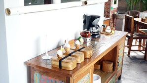 Uma área de bar com madeira, uma máquina de café, um bule de chá e objetos decorativos.