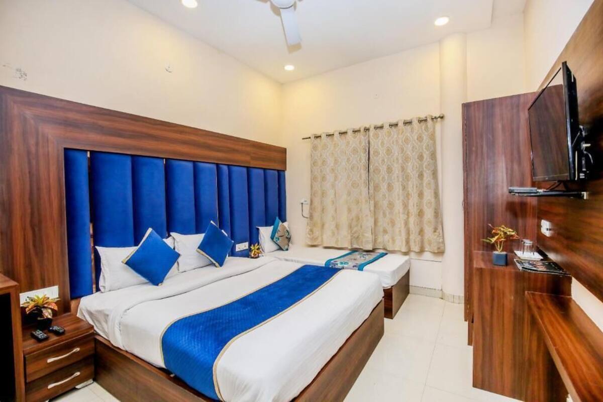 Quarto de hotel com uma cama grande, televisão e guarda-roupa de madeira.