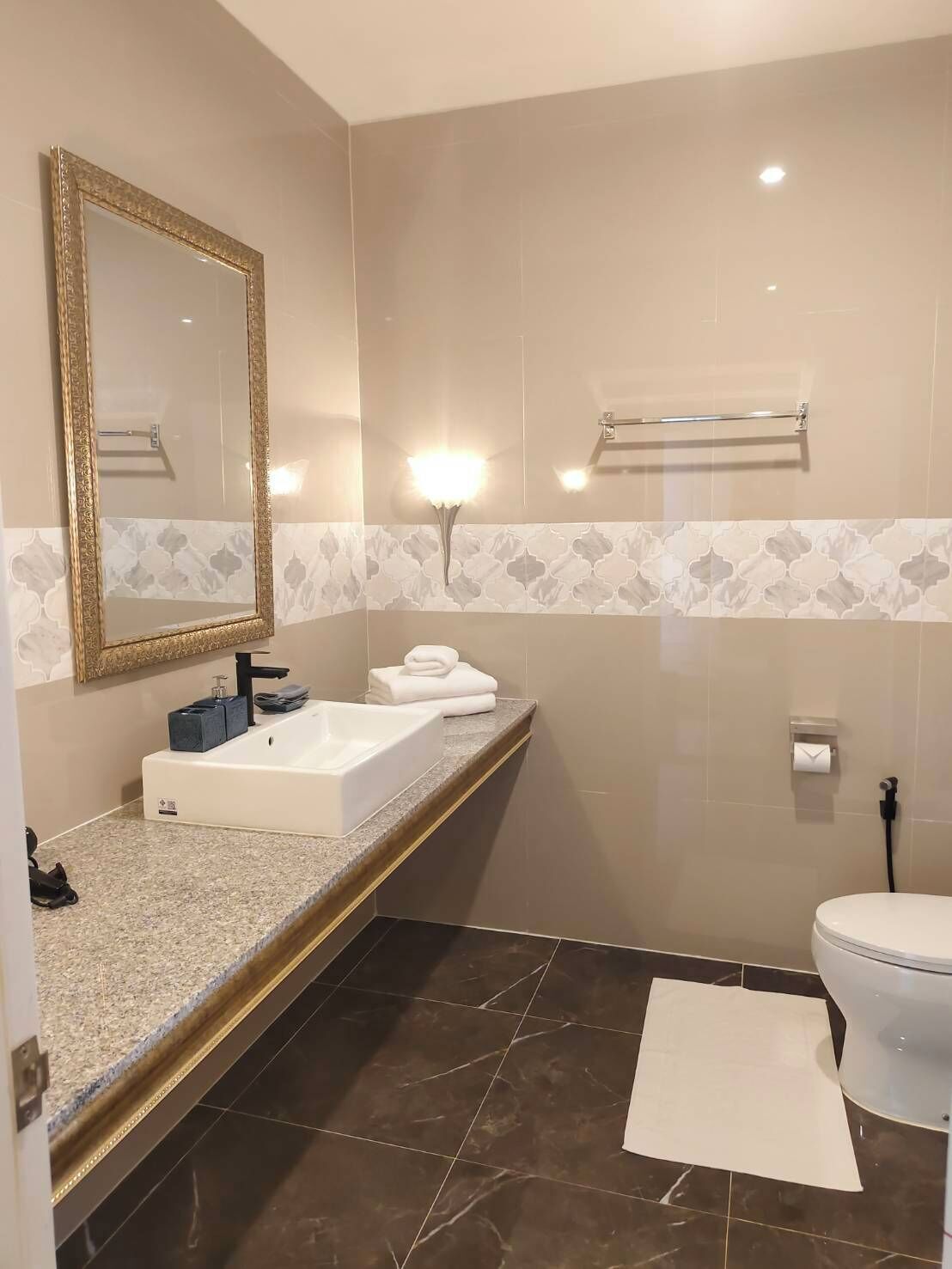 Um banheiro moderno com um espelho grande, uma pia branca, um porta-toalhas e um vaso sanitário.