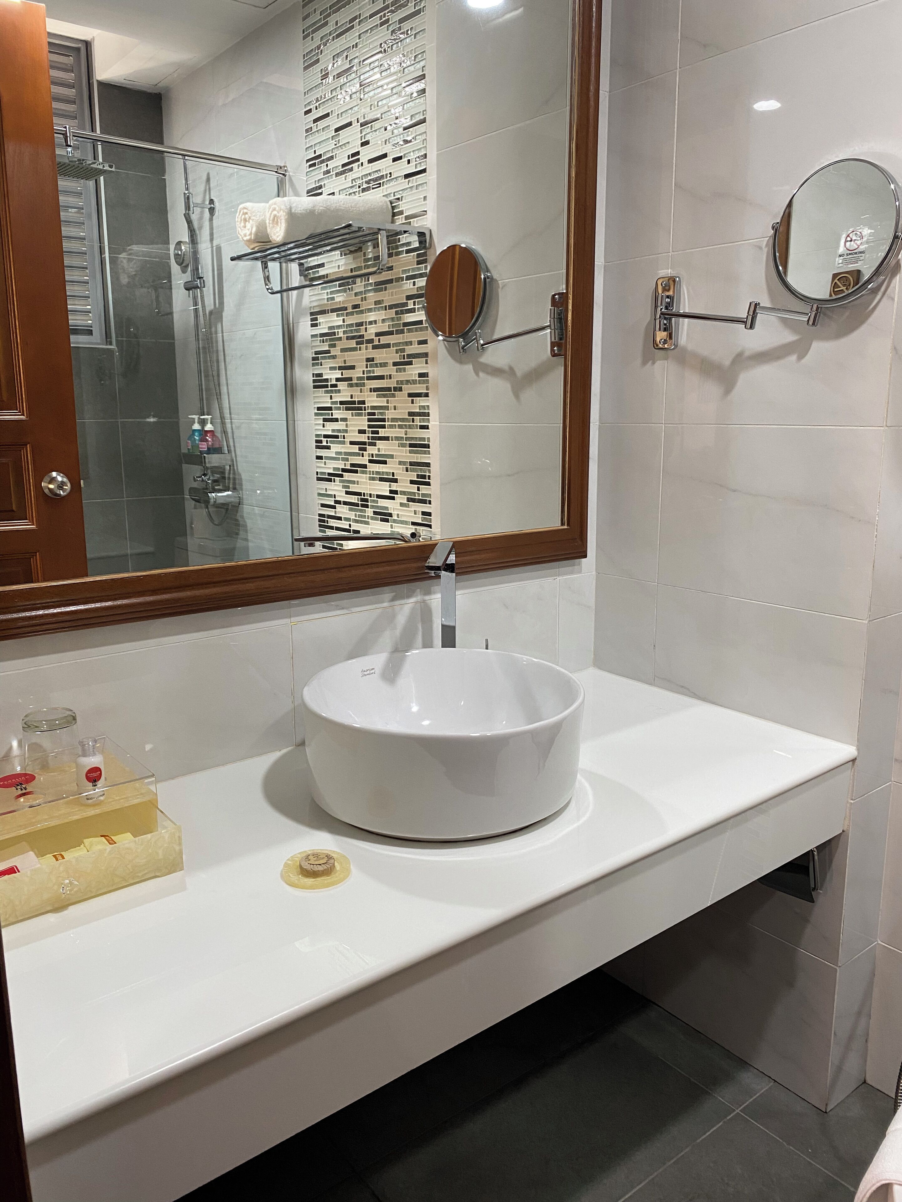 Casa de banho com lavatório branco, espelho e área de duche.