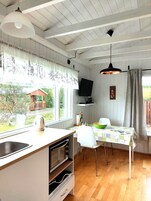 Uma cozinha com bancada de madeira, pia, fogão e um espaço de refeições com mesa e cadeiras.