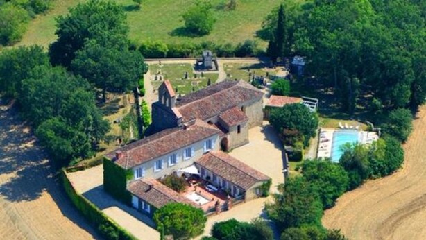 Vista aérea de uma grande propriedade com casa principal, piscina e campos ao redor.