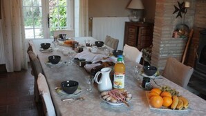 Uma mesa de jantar posta com pratos, tigelas, copos e uma garrafa de suco de laranja.