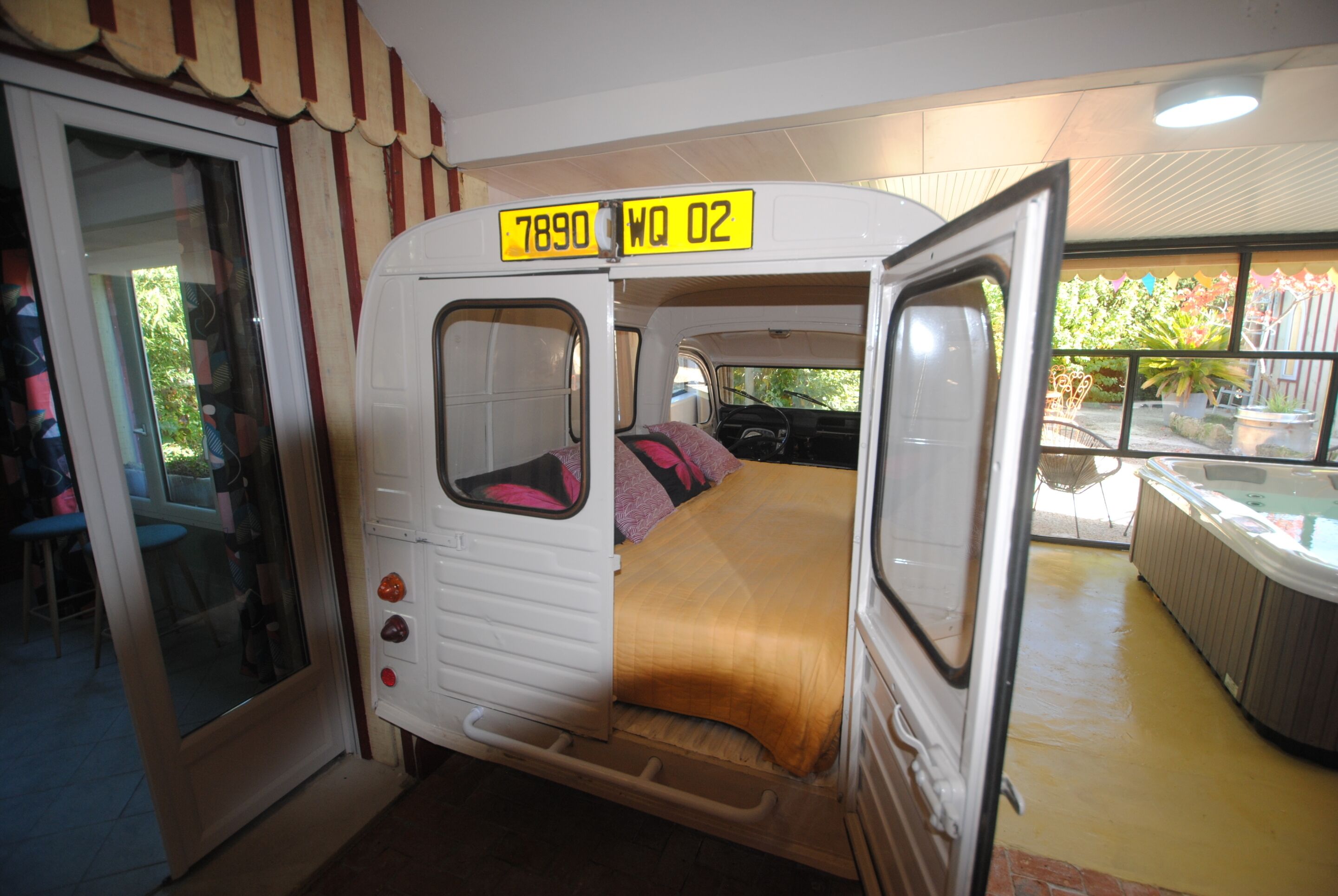 Um autocarro transformado com uma cama, uma pequena janela e uma porta.