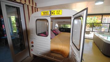 Um autocarro transformado com uma cama, uma pequena janela e uma porta.