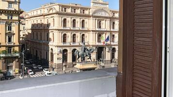 Um edifício histórico com arquitetura clássica, uma estátua em frente e vista clara para a rua.
