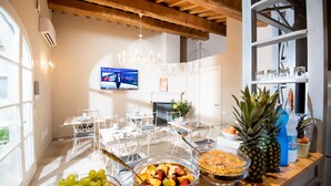 Buffet de café da manhã com diversas frutas e uma televisão exibindo um canal de notícias.