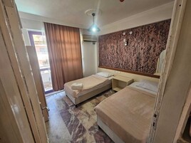 Quarto de hotel com duas camas, um espelho grande, um ventilador de teto e vista para o exterior.