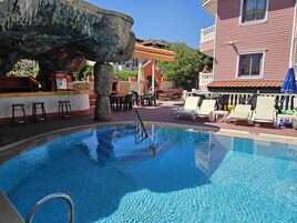 Piscina com espreguiçadeiras e bar.