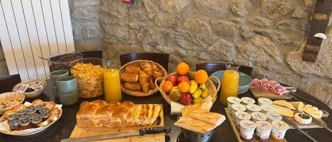 Buffet de café da manhã com diversos alimentos e um fundo de parede de pedra.