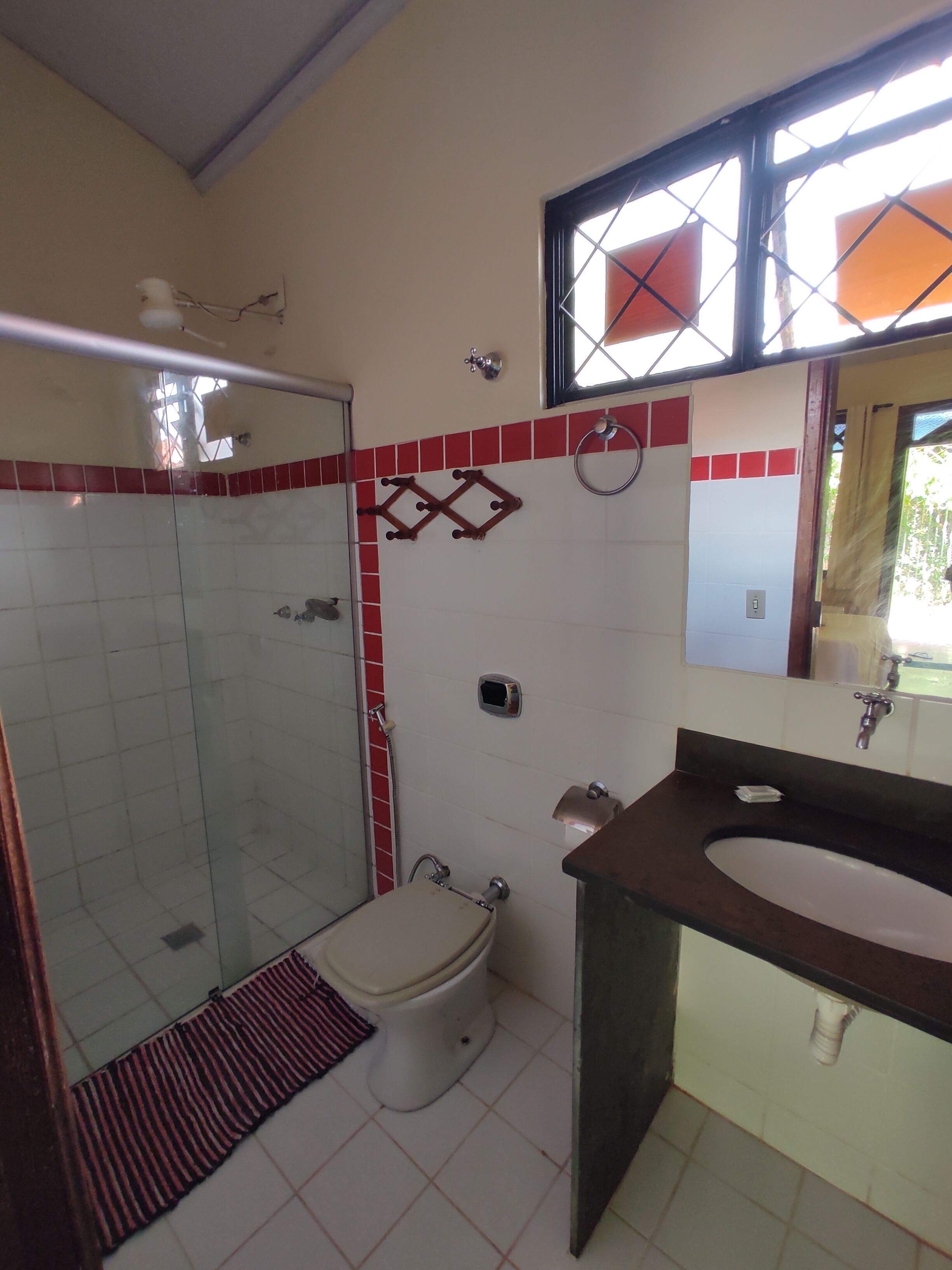 Uma casa de banho com cabine de duche em vidro, sanita e lavatório com espelho.