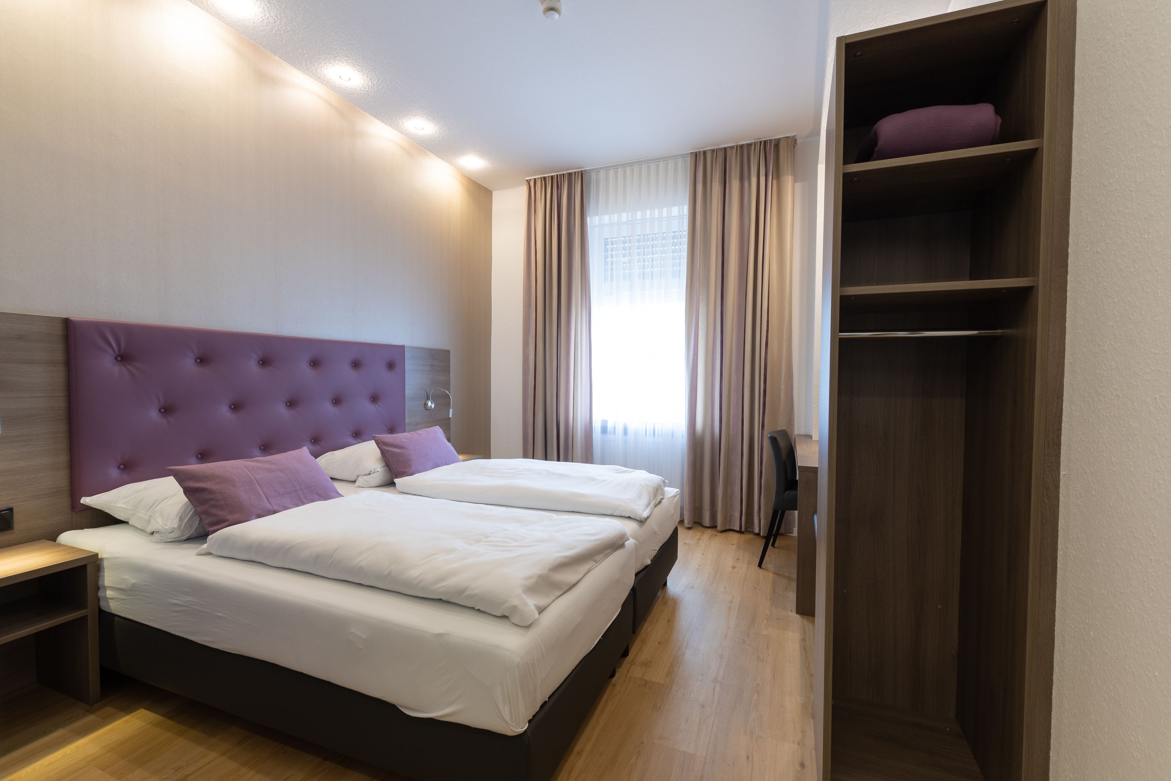 Quarto de hotel moderno com uma cama grande, um guarda-roupa e uma mesa.