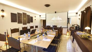 Uma sala de conferências com uma mesa comprida, cadeiras, laptops, garrafas de água e uma tela de projetor exibindo um logotipo.