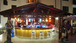 Área de bar ao ar livre com balcão, banquetas e uma estátua de pirata.