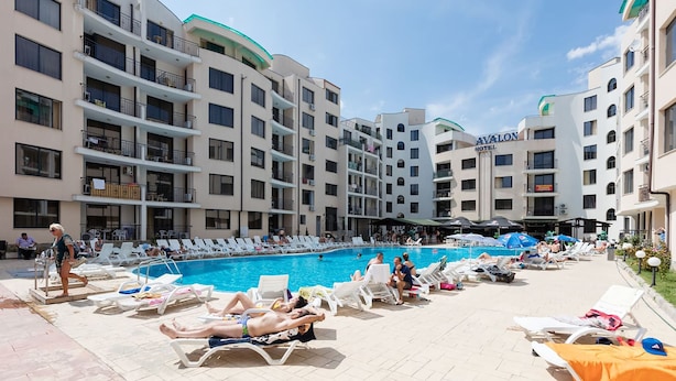 Um hotel com área de piscina, várias varandas e uma placa indicando o Hotel Avalon.