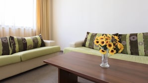 Uma sala de estar com dois sofás, uma mesa de centro e um vaso com girassóis.