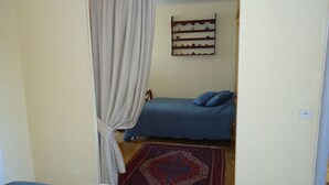 Quarto com duas camas, prateleira suspensa e tapete estampado.