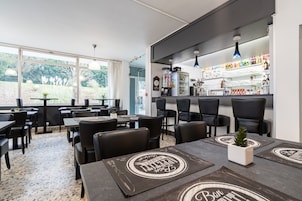 Restaurante com área externa, bar e vista para o jardim.