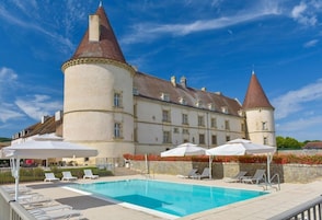 Um castelo com piscina, espreguiçadeiras e guarda-sóis.