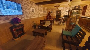 Uma sala de estar acolhedora com lareira, móveis de madeira, televisão e um pinheiro de Natal.