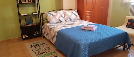 Quarto com cama, estante, guarda-roupa e um tapete decorativo.