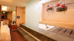 Quarto de hotel com uma cama, uma mesinha e um espelho. Inclui banheiro com pia e espelho.