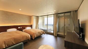 Quarto de hotel com duas camas, televisão, mesa de mármore e varanda com porta de vidro.
