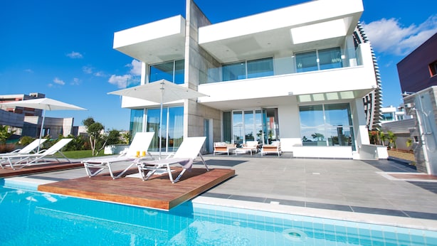 Um edifício moderno de dois andares com piscina e espreguiçadeiras.
