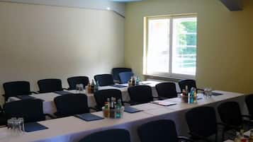 Sala de conferências com uma mesa comprida, cadeiras e uma janela com vista para o verde.