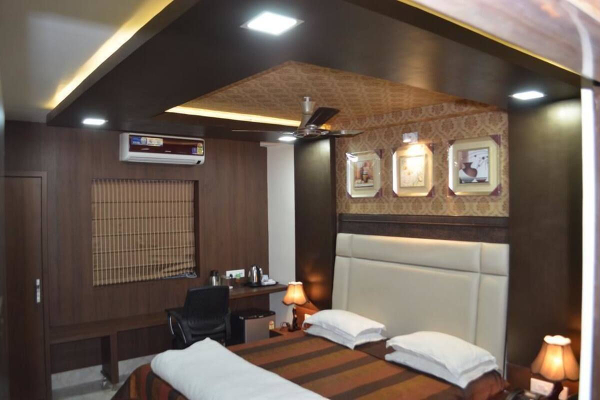 Quarto de hotel com cama, escrivaninha, cadeira e ar condicionado fixado na parede.