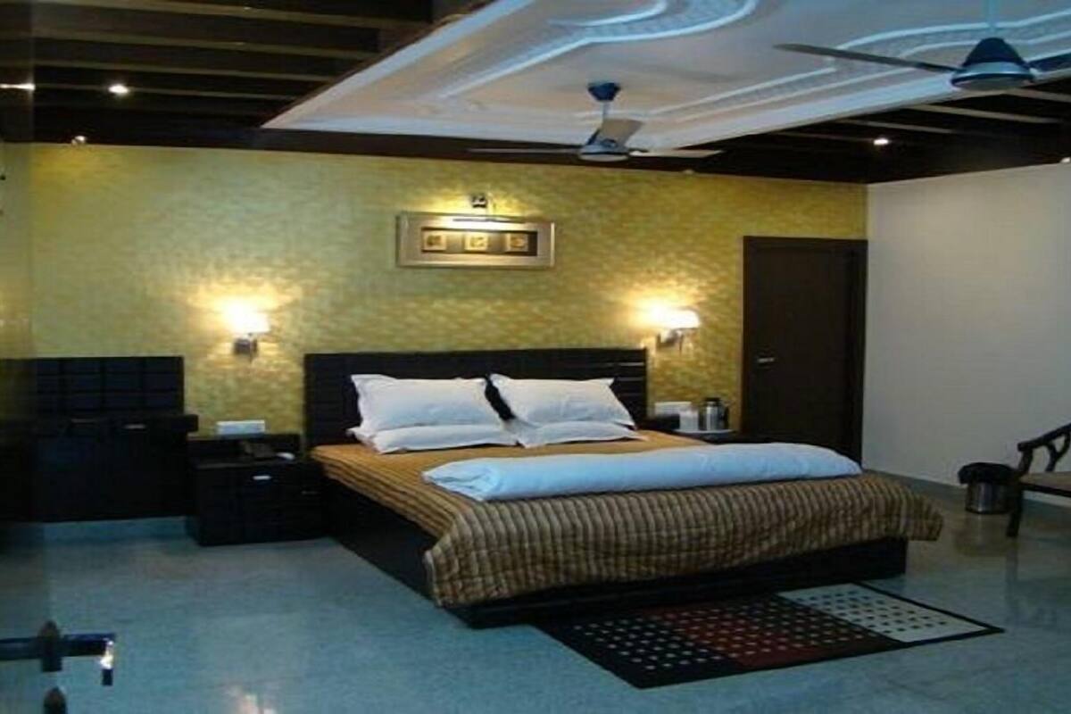 Quarto com cama, mesas de cabeceira, luminária na parede e ventilador de teto.